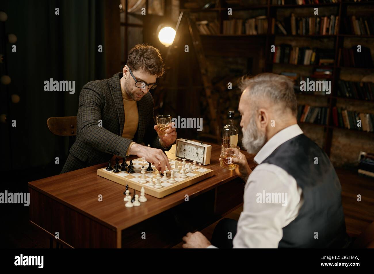 Concentrated chess players holding competition match at home library ...