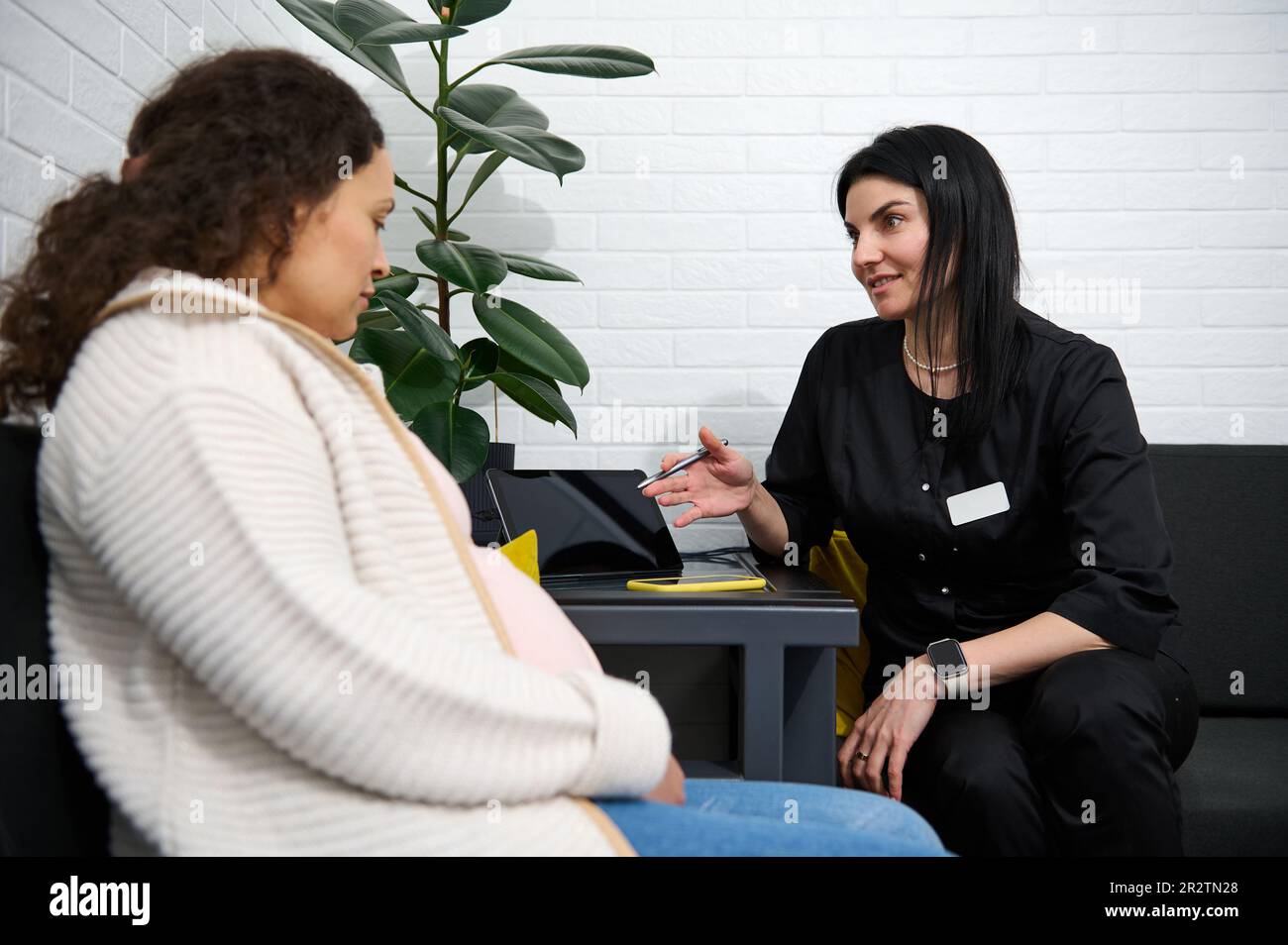 Medical worker consults pregnant female patient in the central hall of ...
