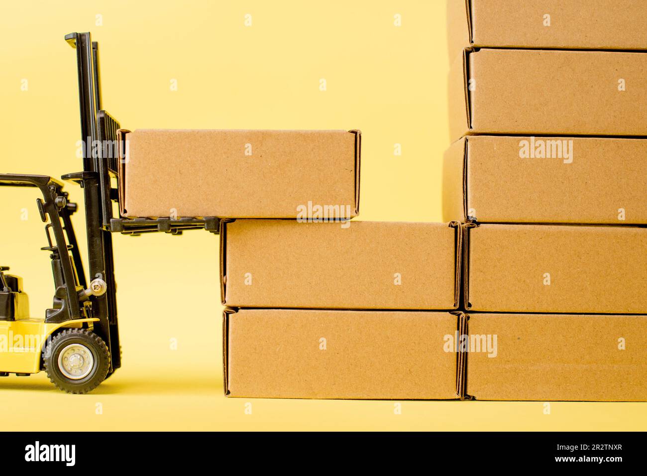 Forklift truck raises cardboard boxes on a yellow background. Cargo ...