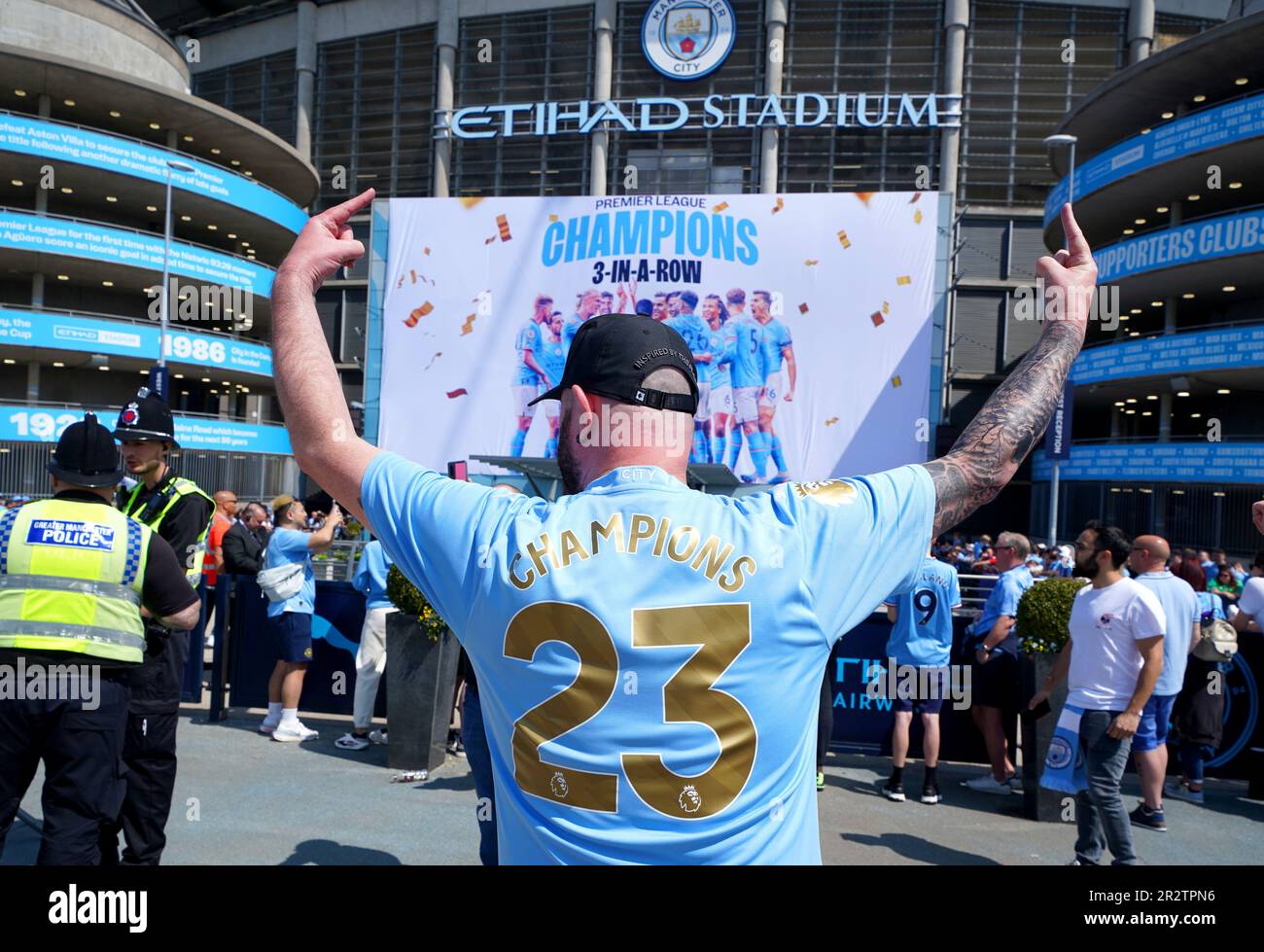 A Manchester City fan poses for a photo in front of a banner ...