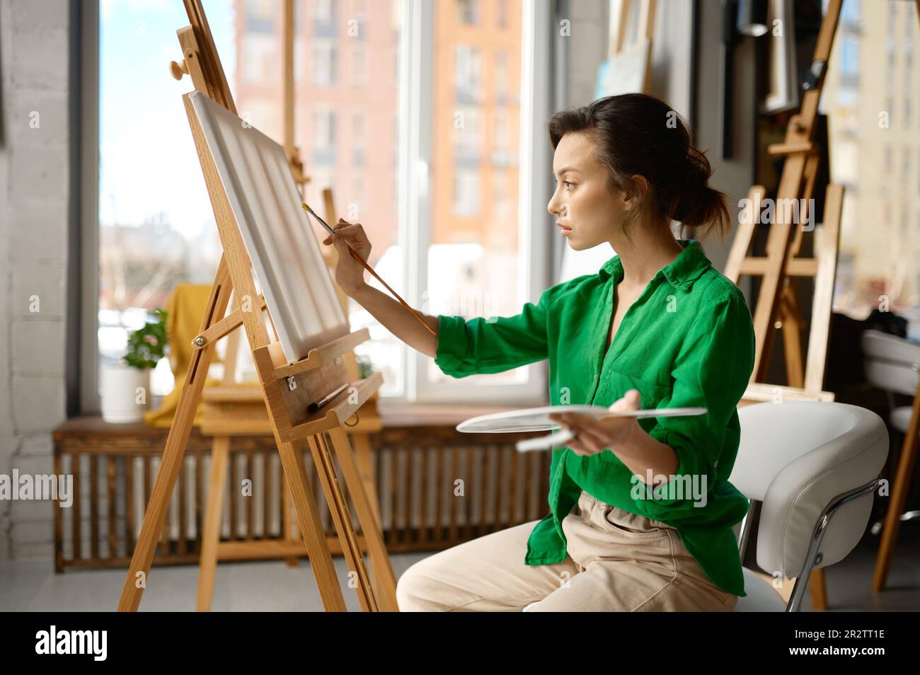 Woman painting brush on canvas at workshop during art lesson class ...