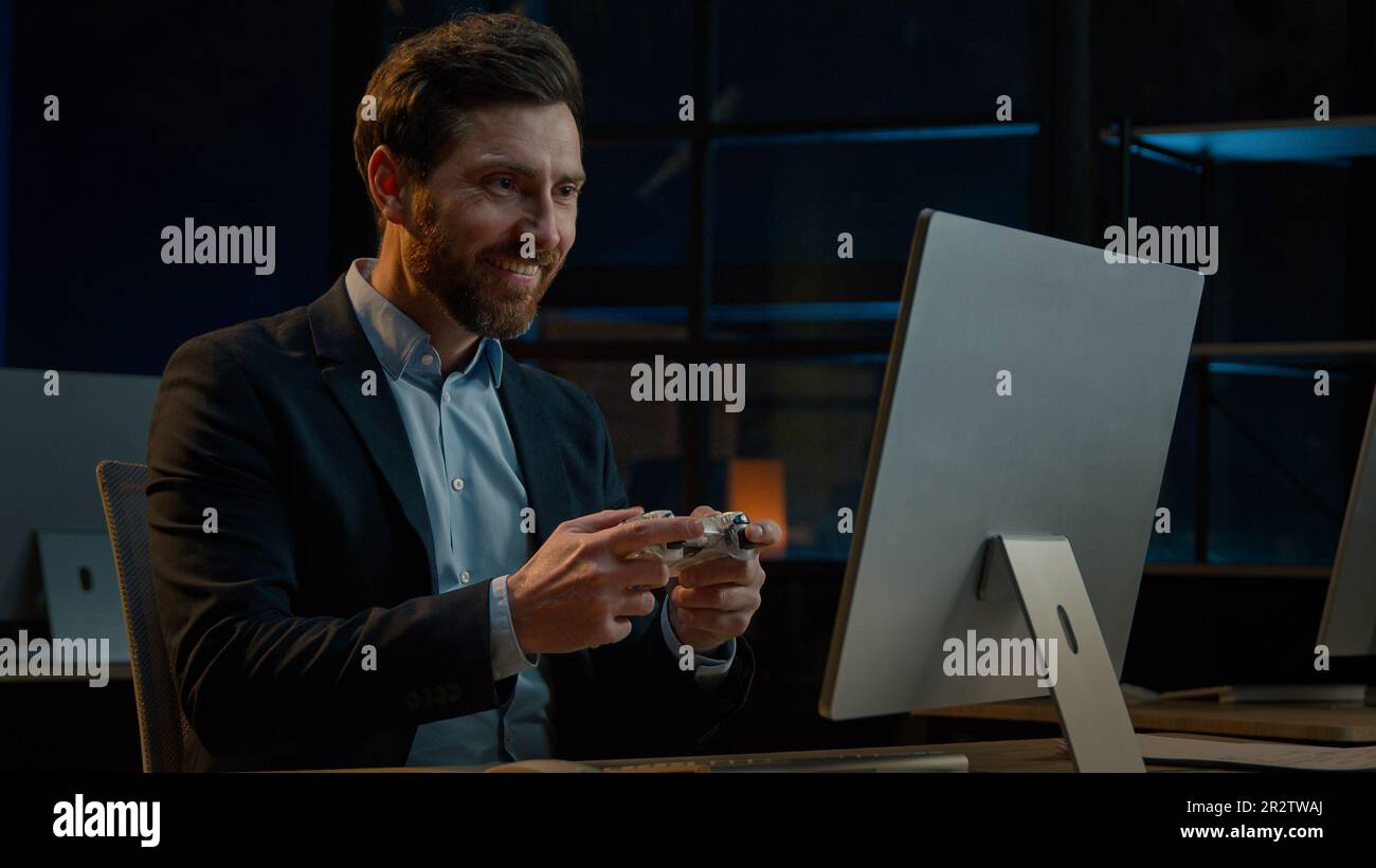 Adult businessman employee working in evening office happy male gamer ...