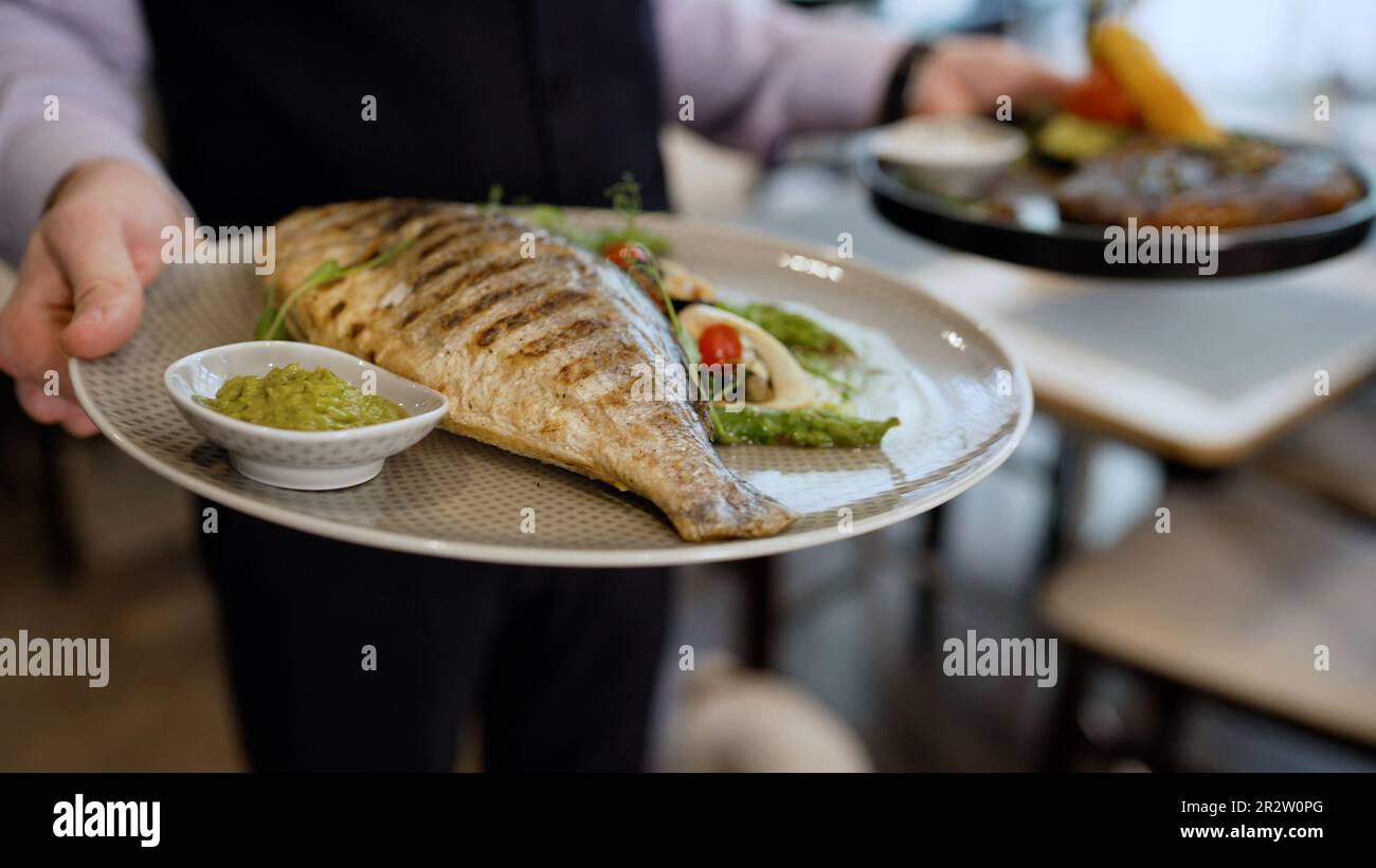 The waiter puts delicious dishes on the table. The waiter puts ...