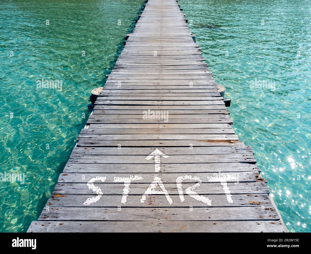 Start, white text and arrow on wooden bridge heading to the sea. Wood ...