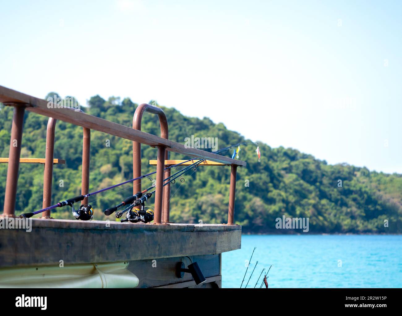 Three fishing rods and spinning reels on the deck of wooden fishing ...