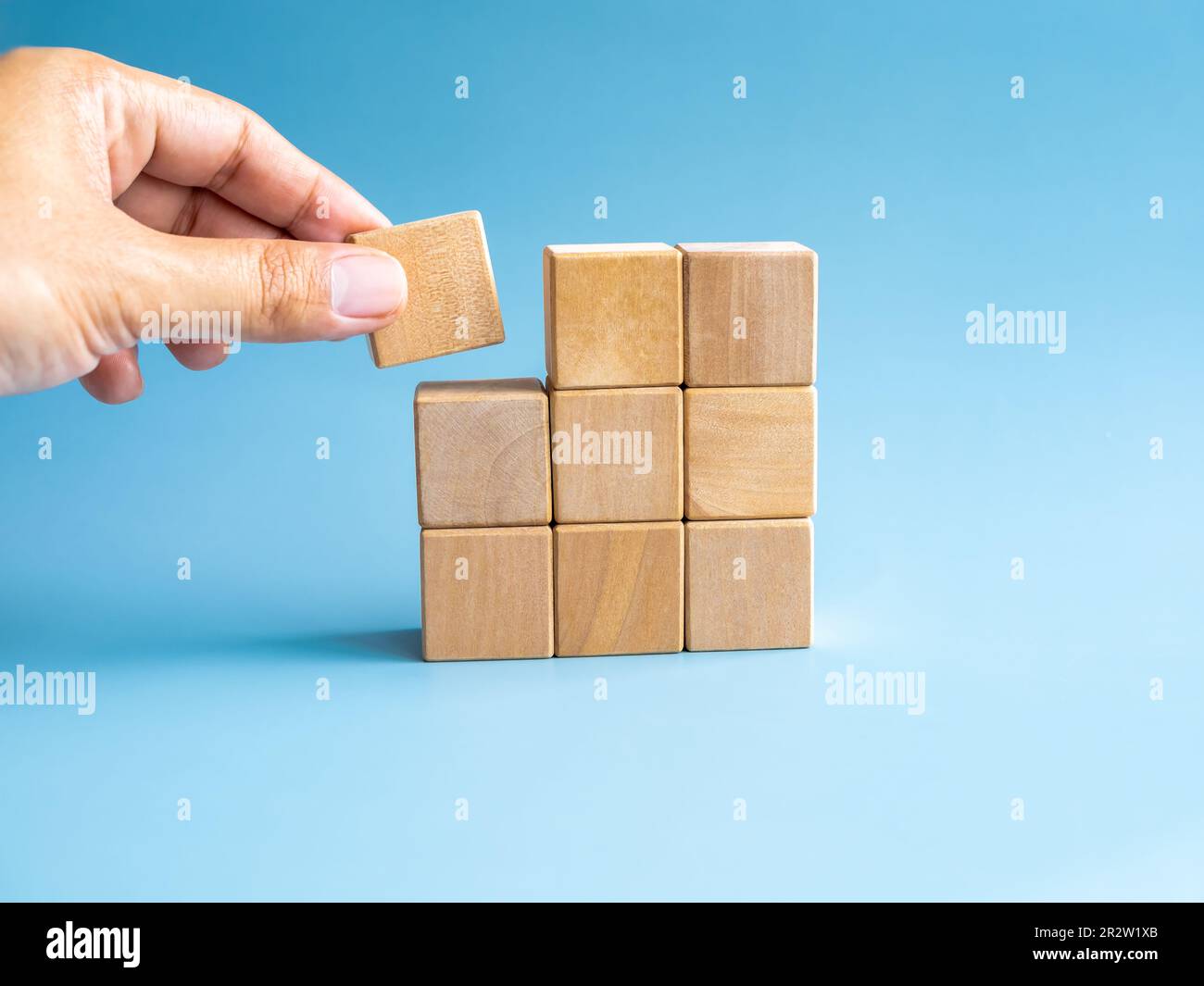 Last piece wood cube block in hand putting on wooden puzzles stacking arranging compleated ...