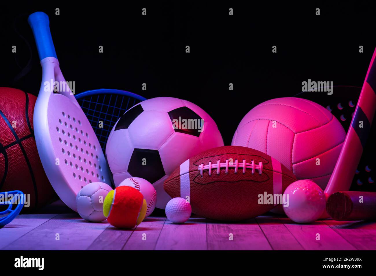 Sports equipment, rackets and balls on hardwood court floor with neon ...