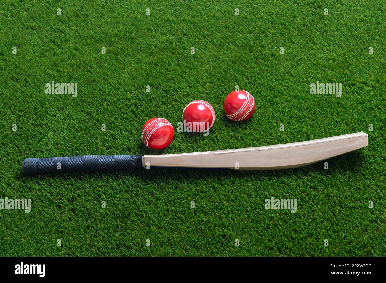 Cricket bat and red ball on green grass background. Horizontal sport ...