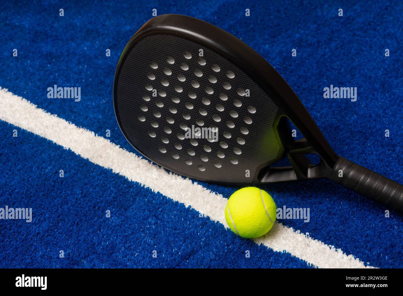 Black professional paddle tennis racket and ball with natural lighting ...