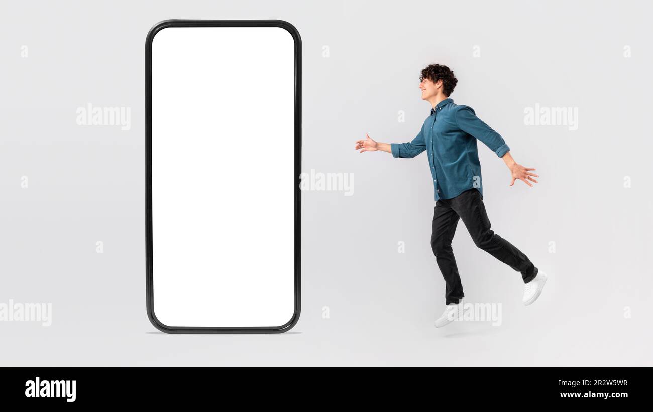 Joyful Man Jumping Looking At Big Phone Screen, White Background Stock ...