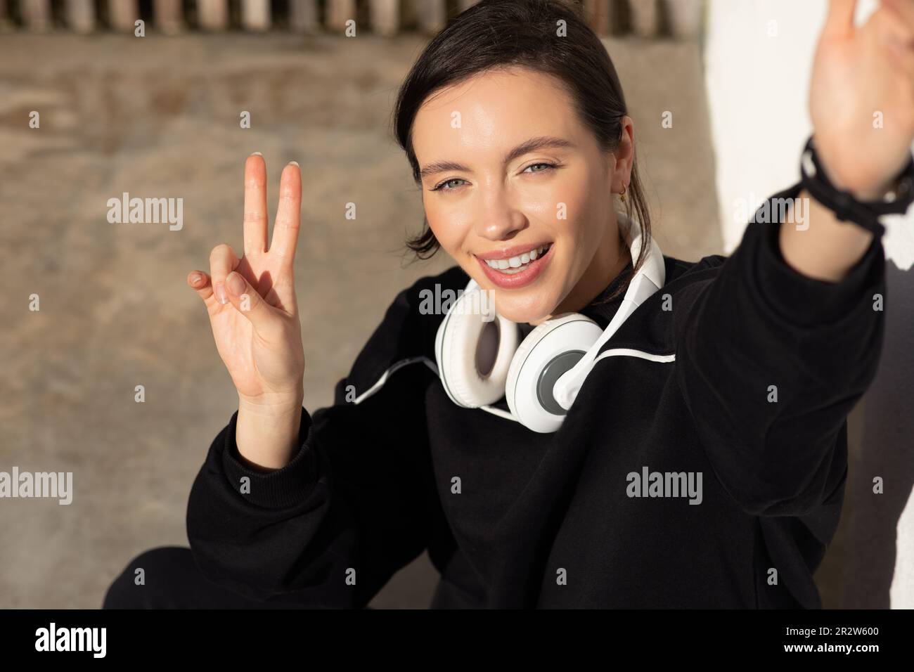 Cheerful young caucasian slim lady with wireless headphones makes ...