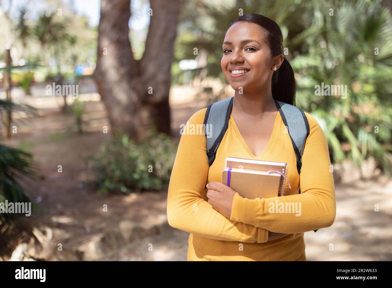 Portrait of successful student girl posing holding books, smiling at ...