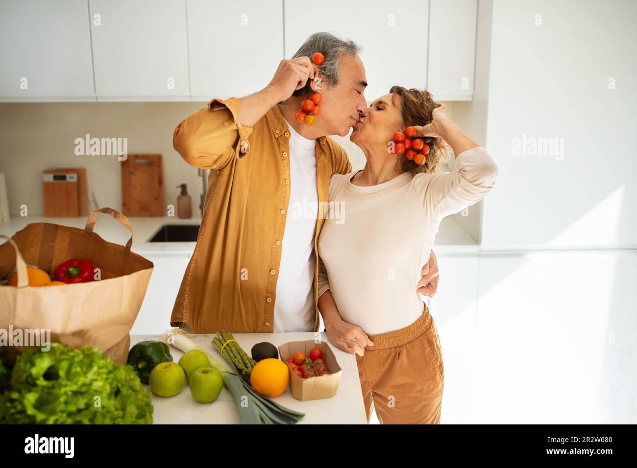 Loving senior spouses arriving from supermarket with grocery bag and ...