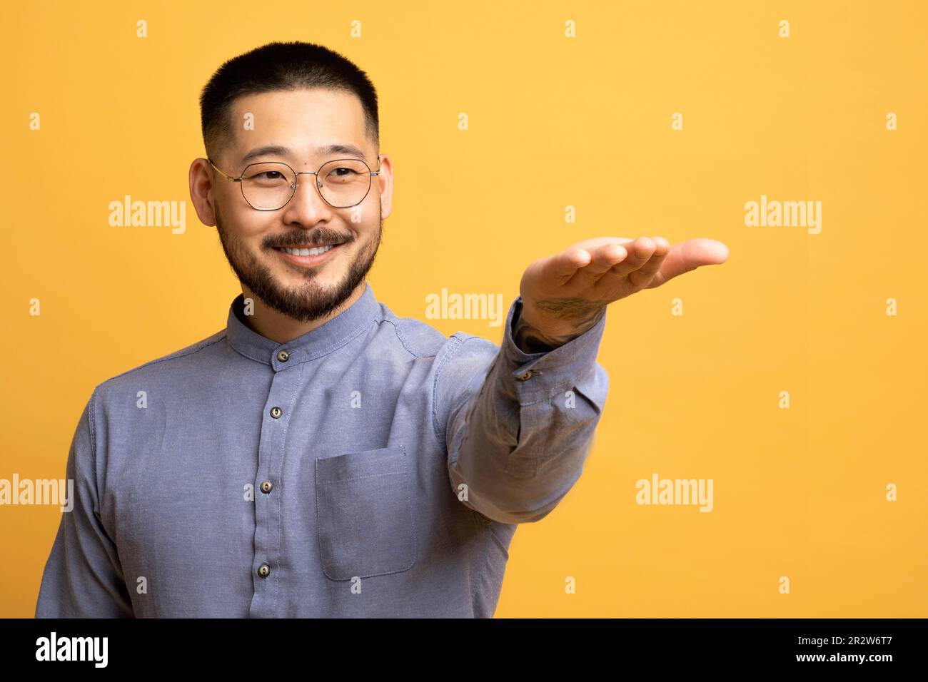 Smiling young asian male outstretching hand, holding something ...