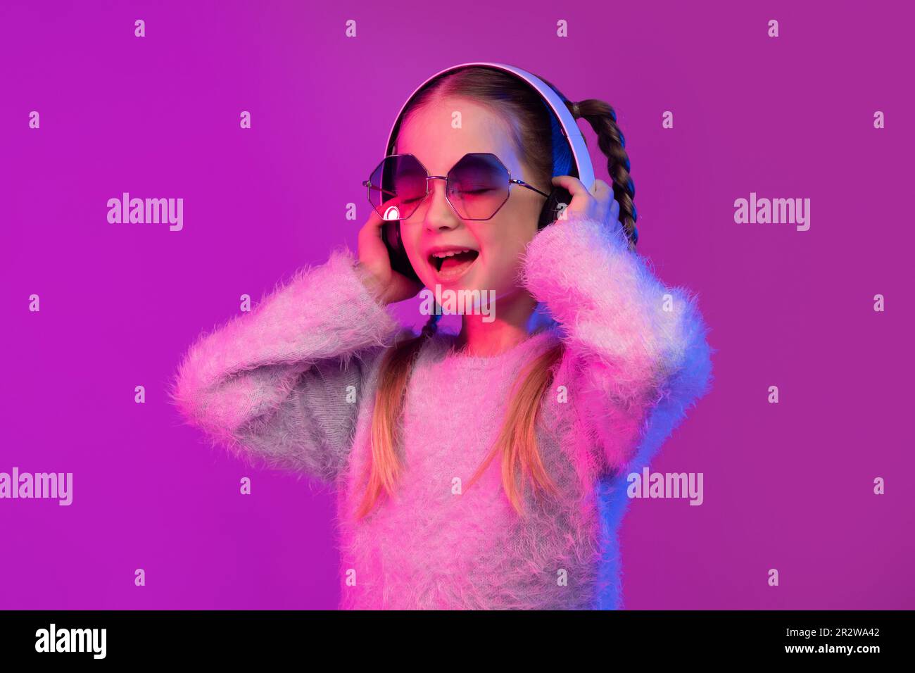 Joyful cute little girl using wireless headphones in neon light Stock ...