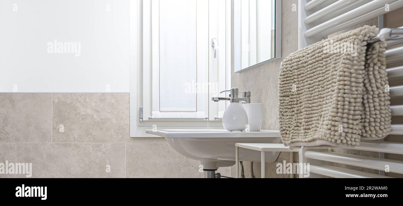 Modern bathroom. Sink with soap and towel on white radiator. Toilet ...