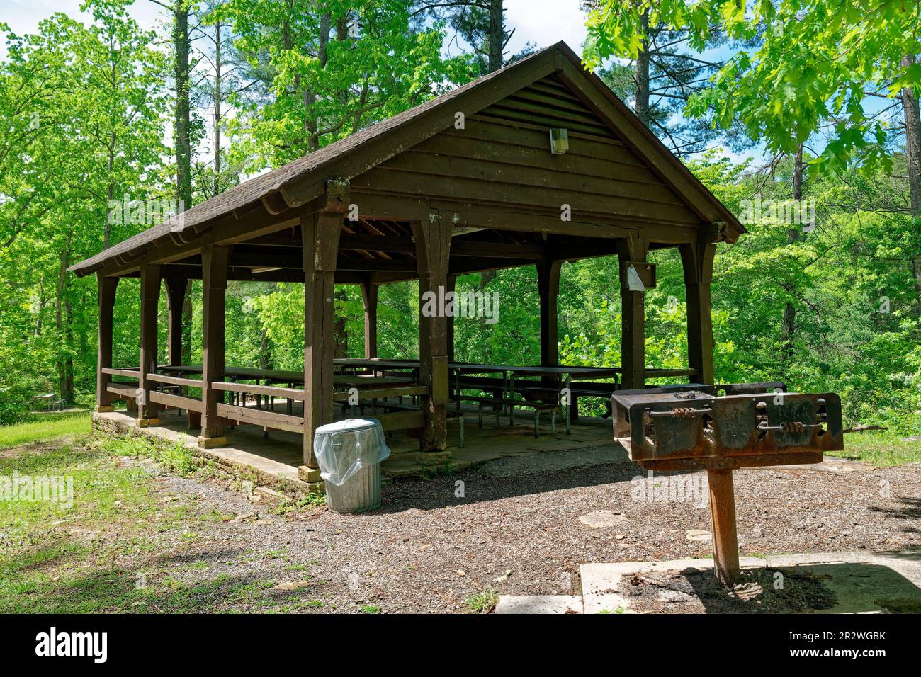 A rustic and worn picnic pavilion with a rusty large grill and a metal ...