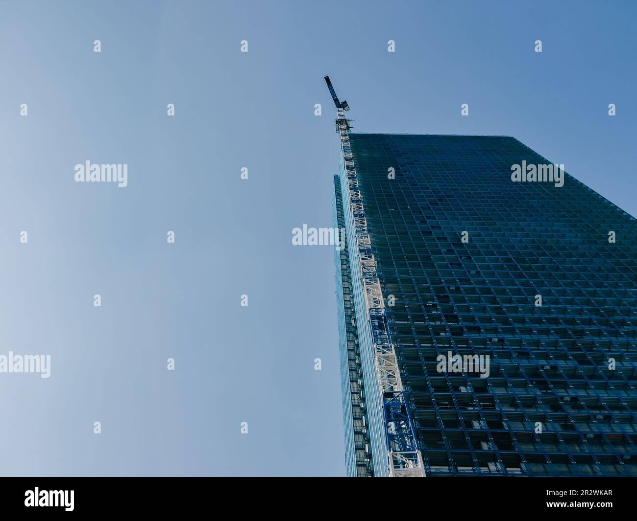 Tall tower crane builds a huge skyscraper against a blue sky Stock ...
