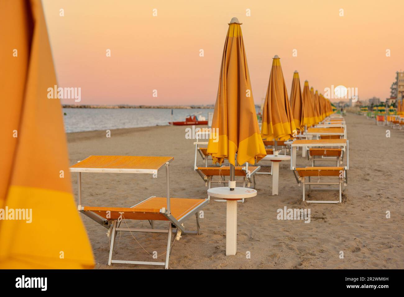 Sun loungers and closed umbrellas on the sea beach on background of ...