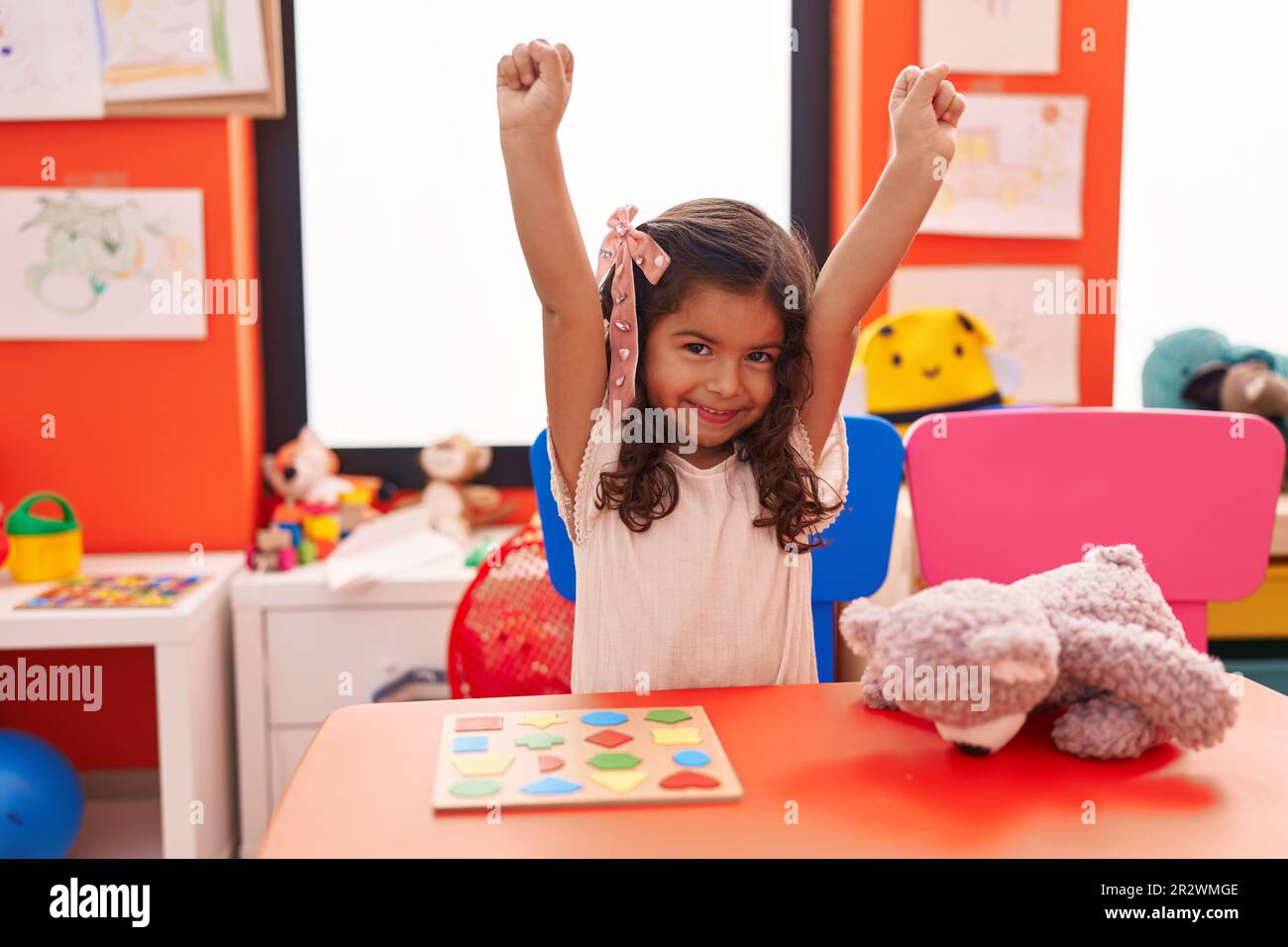 Adorable hispanic girl playing with maths puzzle game doing winner ...