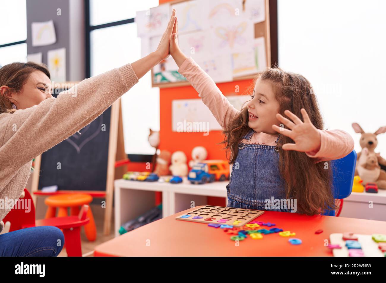 Adorable hispanic girl playing with maths puzzle game high five at ...