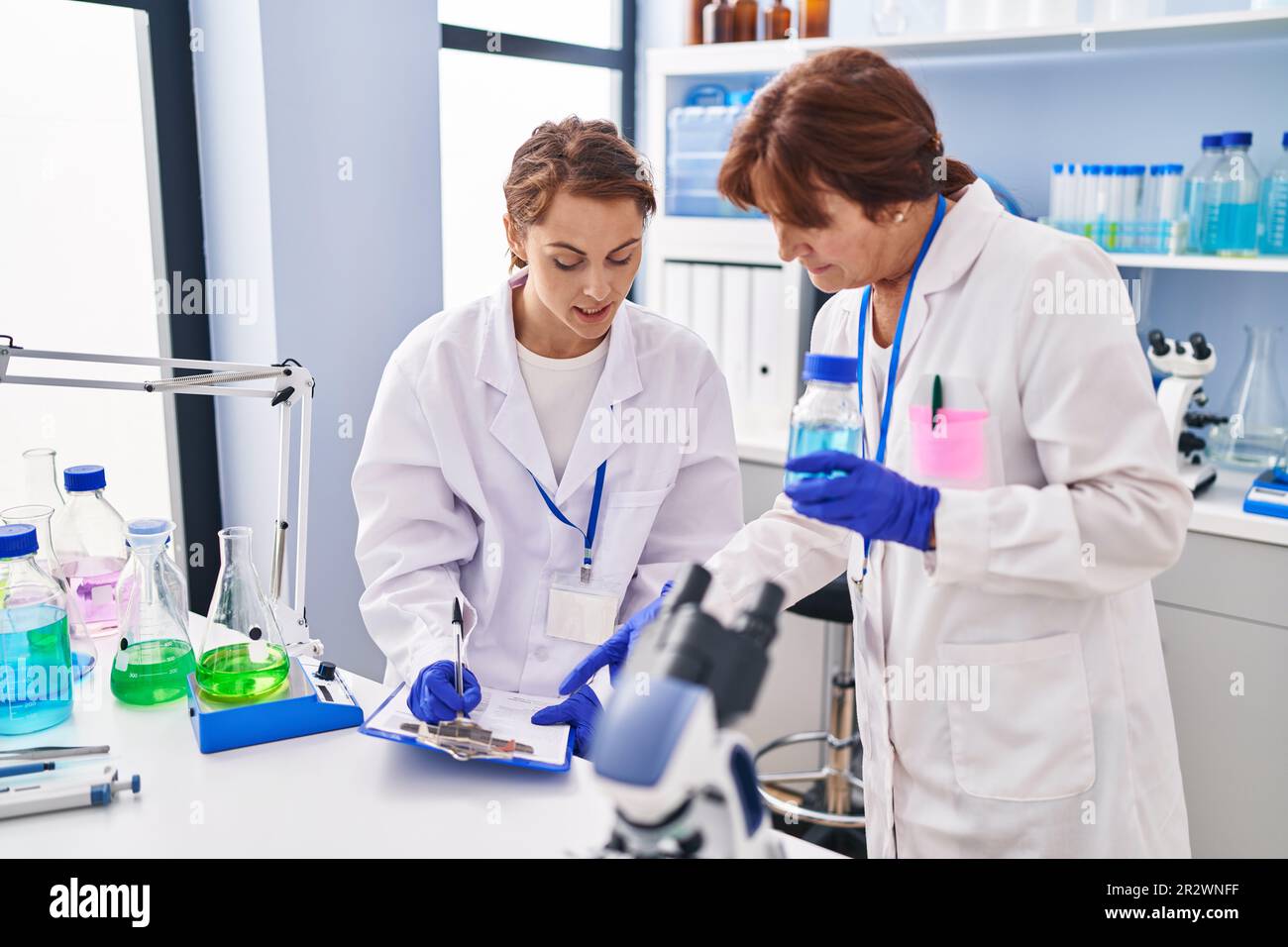 Two women scientists holding test tube writing on document at ...