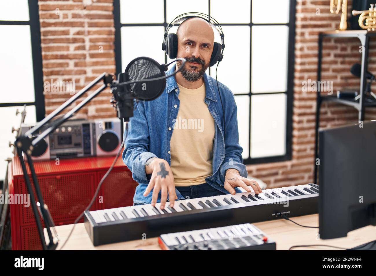 Young bald man musician smiling confident playing piano at music studio ...