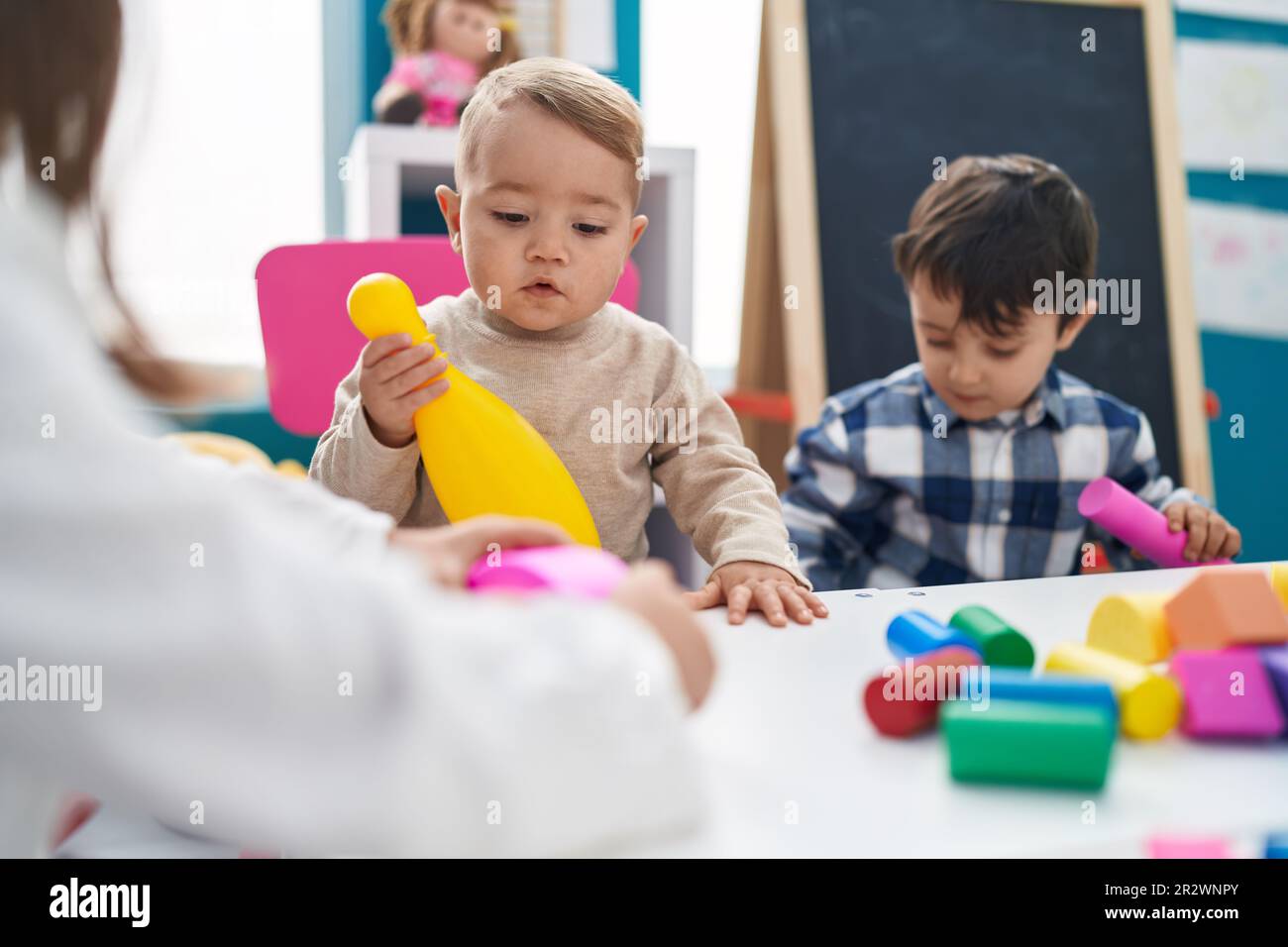 Adorable boys playing with construction blocks holding bowling pin at ...