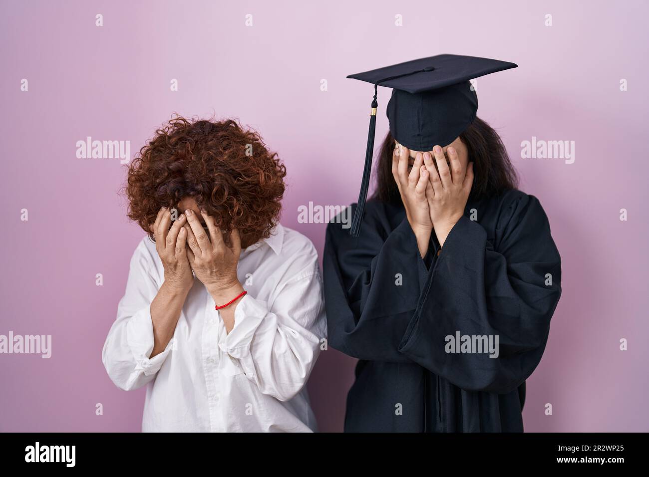 Hispanic mother and daughter wearing graduation cap and ceremony robe ...