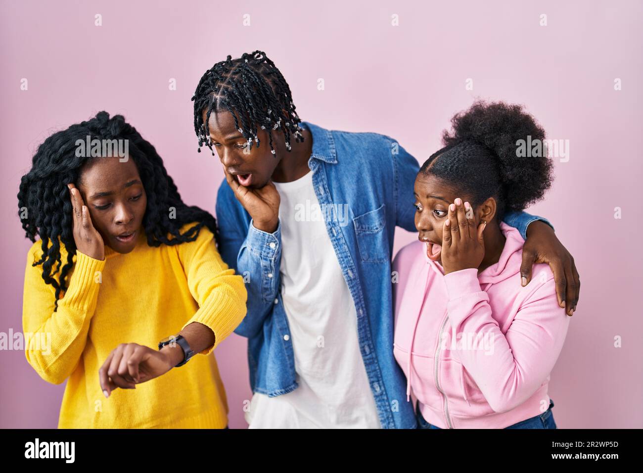 Group of three young black people standing together over pink ...