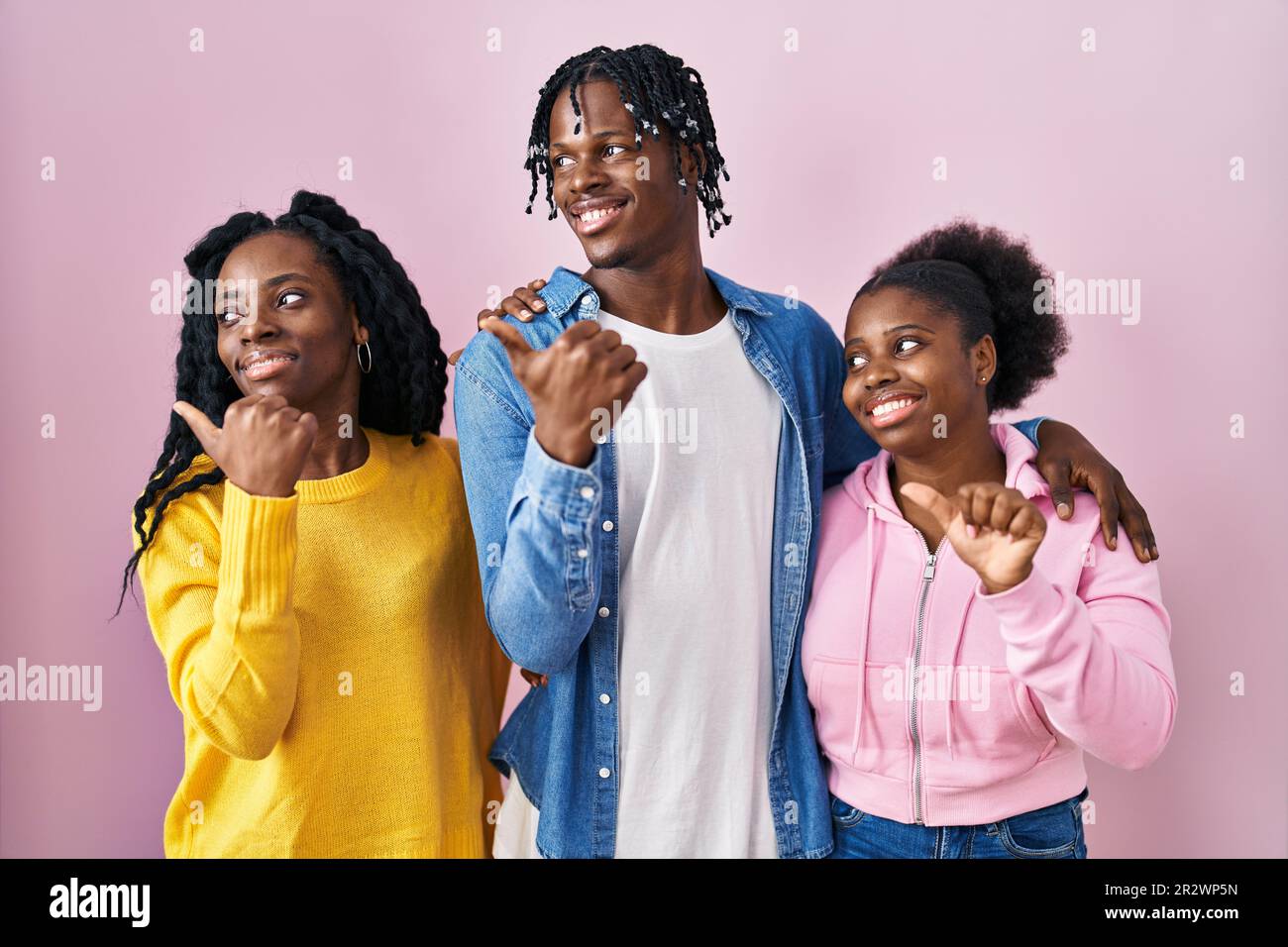 Group of three young black people standing together over pink ...