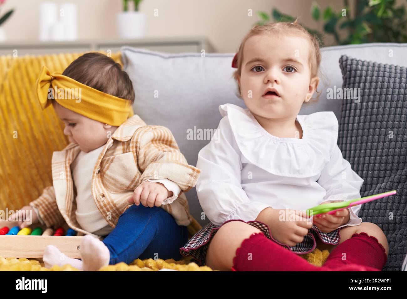 Adorable girls playing with abacus holding scissors at home Stock Photo ...