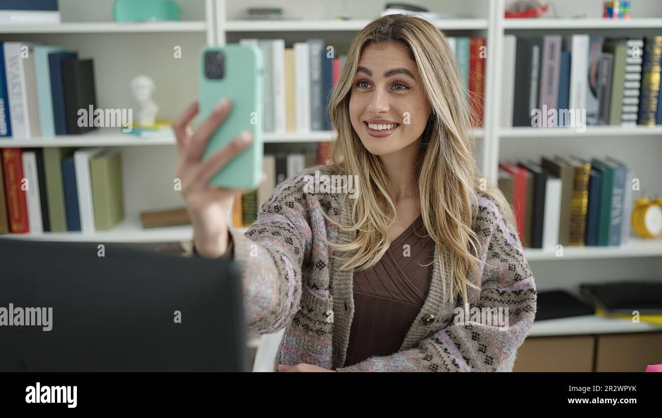 Young blonde woman student having video call at library university ...