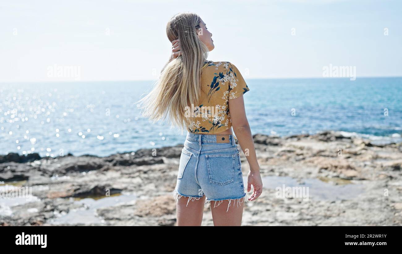 Young blonde woman combing hair backwards at seaside Stock Photo - Alamy