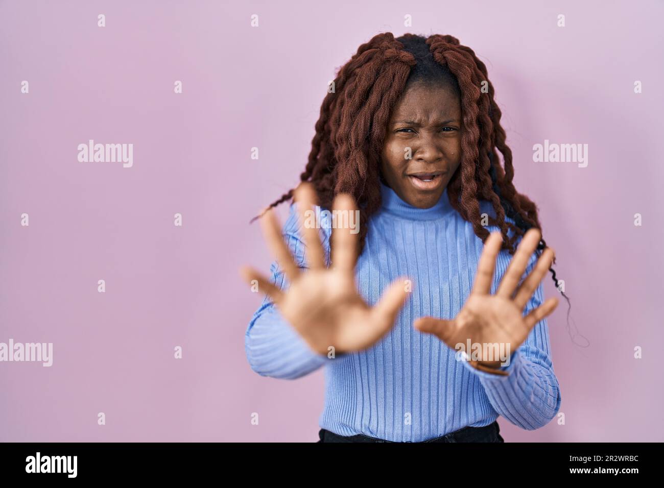 African woman standing over pink background afraid and terrified with ...