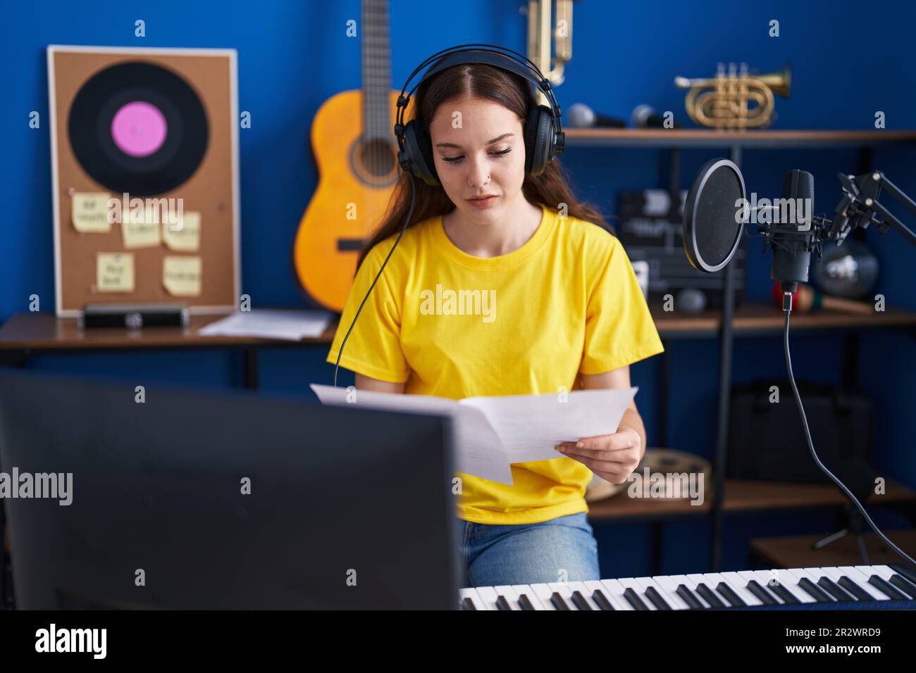 Young woman musician listening to music reading song at music studio ...