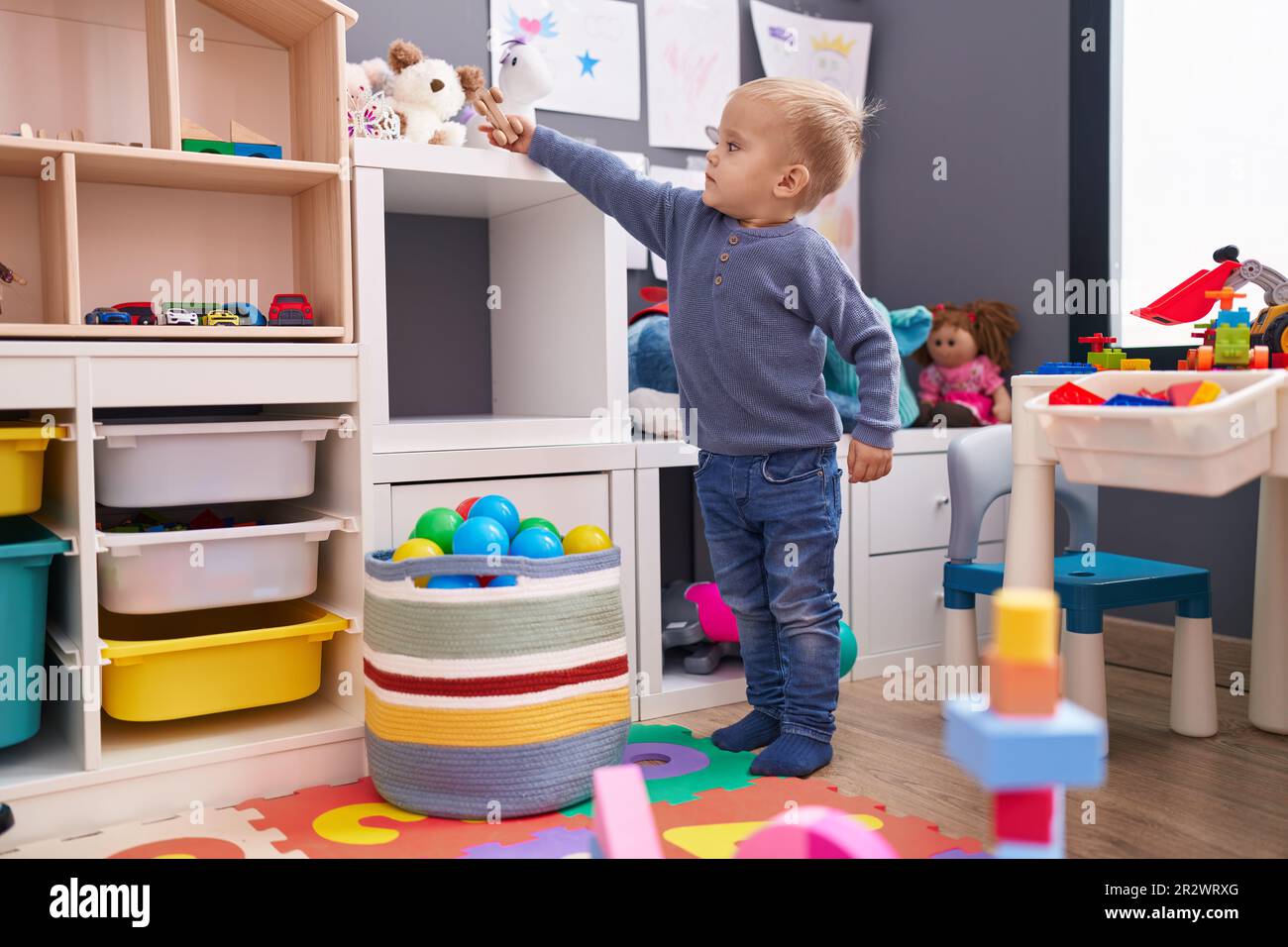 Adorable caucasian boy standing with relaxed expression playing at ...
