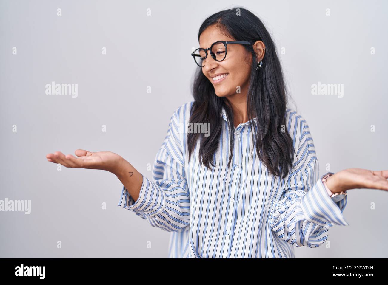 Young hispanic woman wearing glasses smiling showing both hands open ...