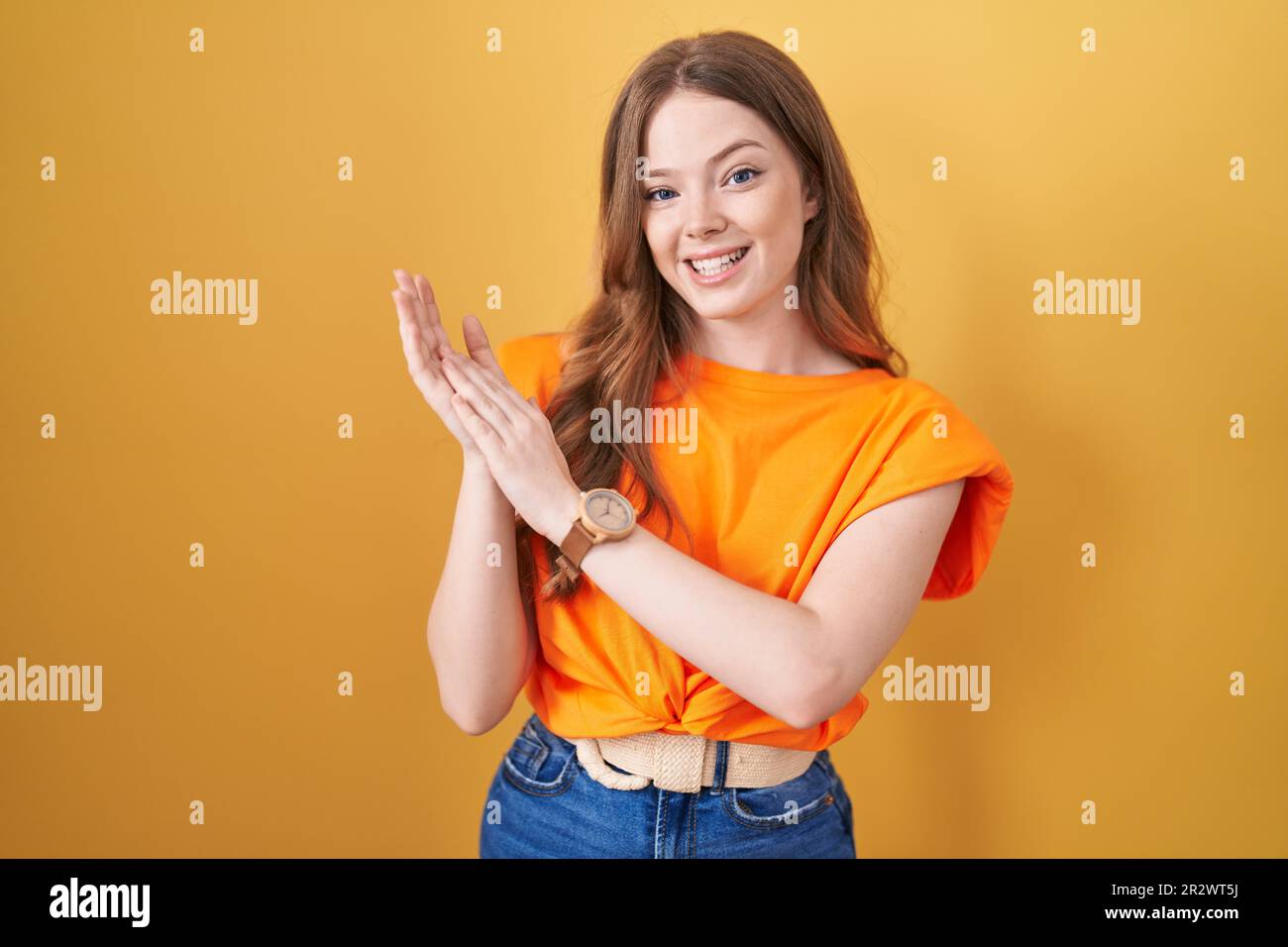 Caucasian woman standing over yellow background clapping and applauding ...