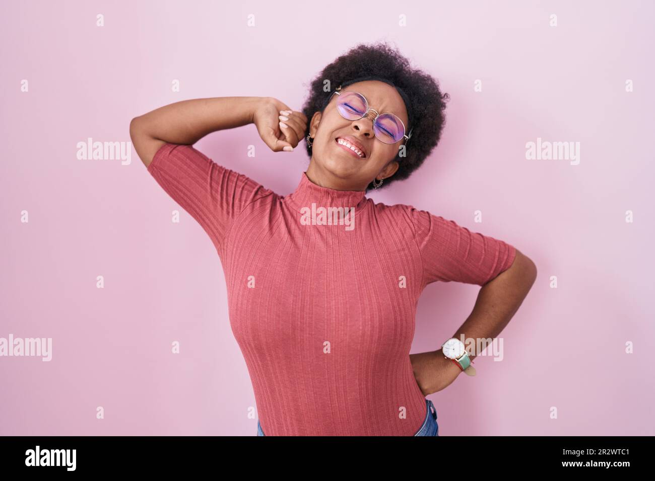 Beautiful african woman with curly hair standing over pink background ...