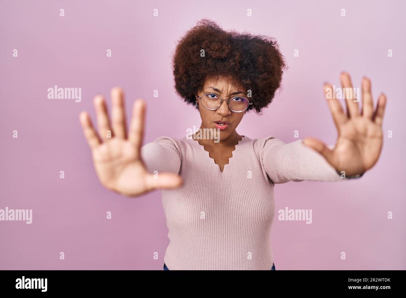 Young african american woman standing over pink background doing stop ...