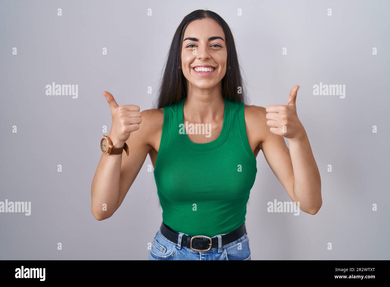 Young woman standing over isolated background success sign doing ...