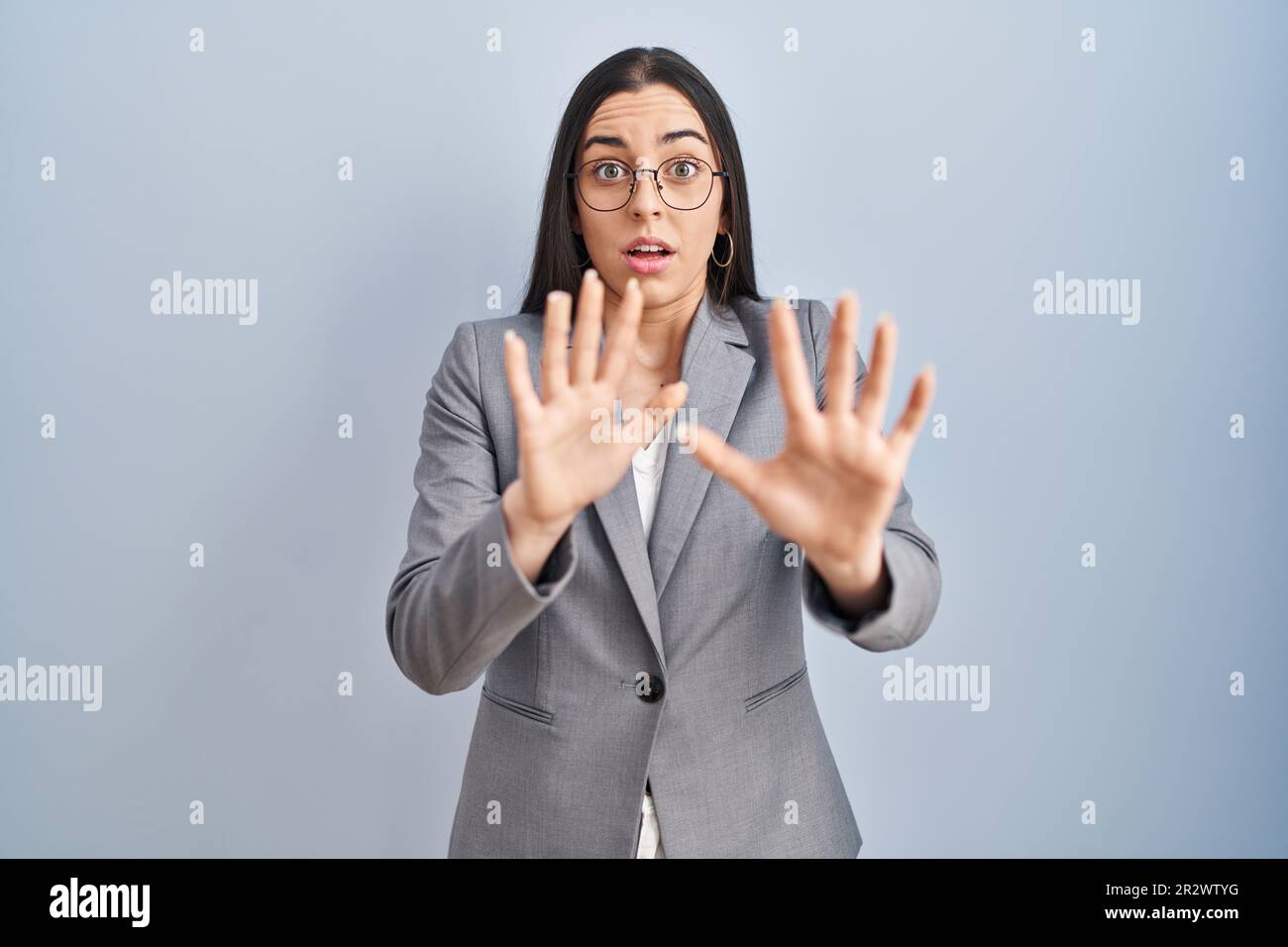 Hispanic business woman wearing glasses afraid and terrified with fear ...