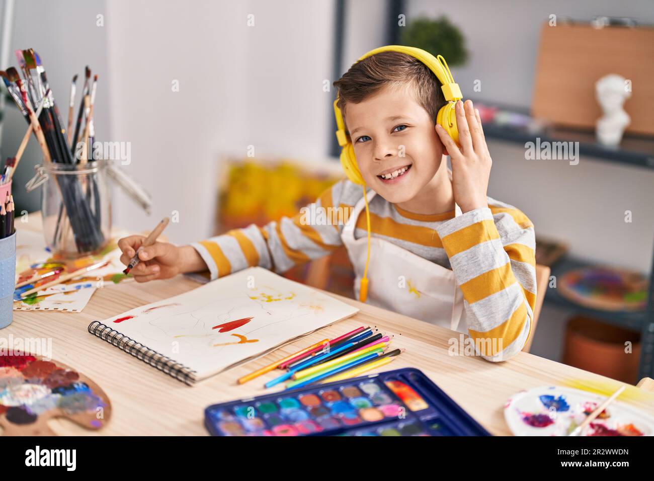 Blond child listening to music drawing at art studio Stock Photo - Alamy