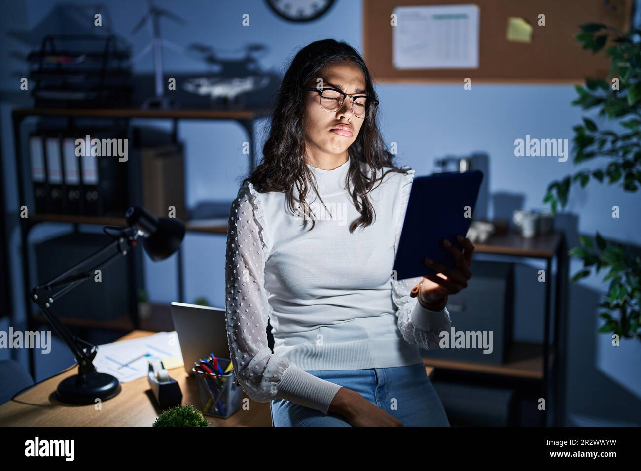 Young brazilian woman using touchpad at night working at the office ...