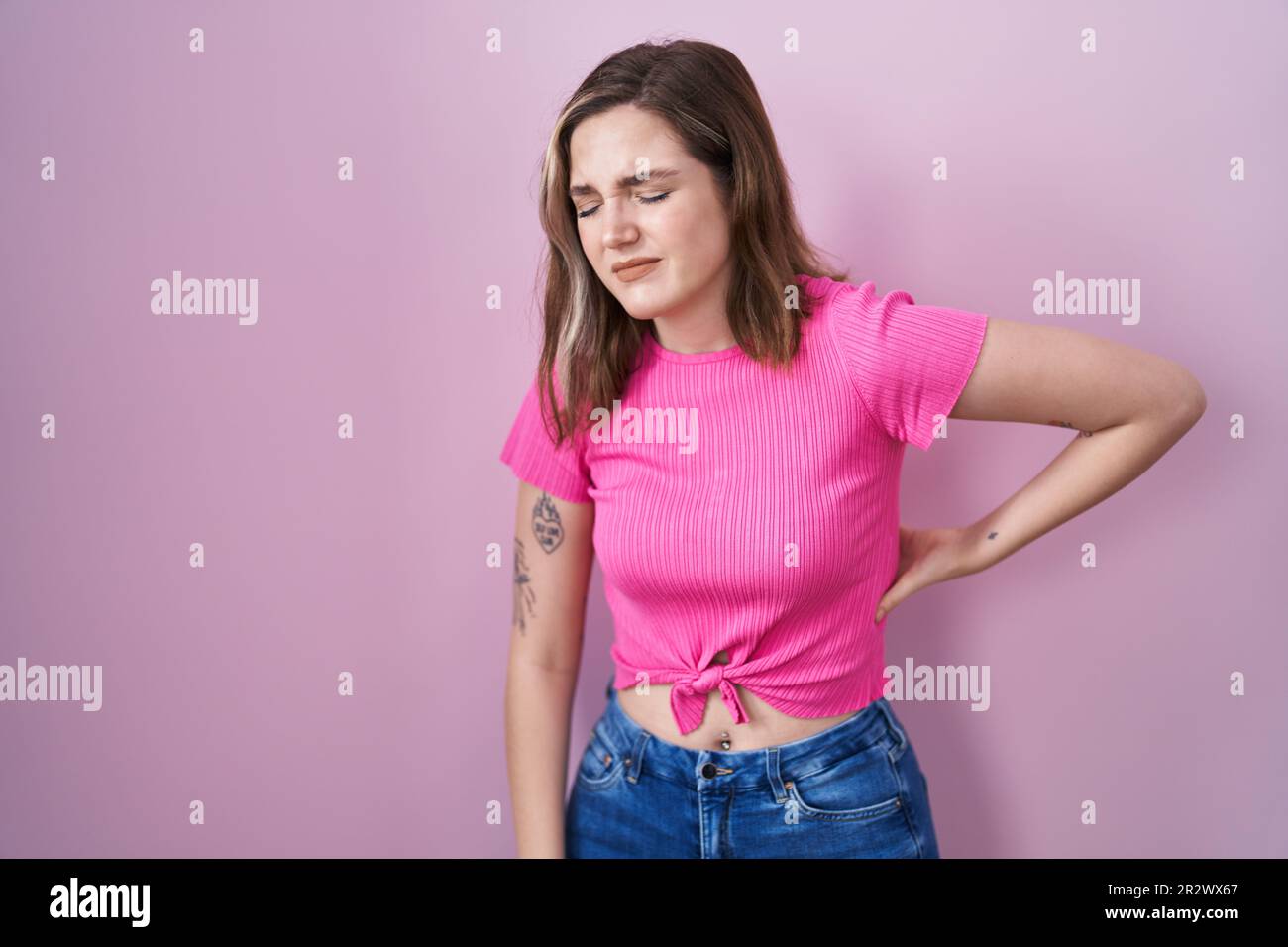 Blonde caucasian woman standing over pink background suffering of ...