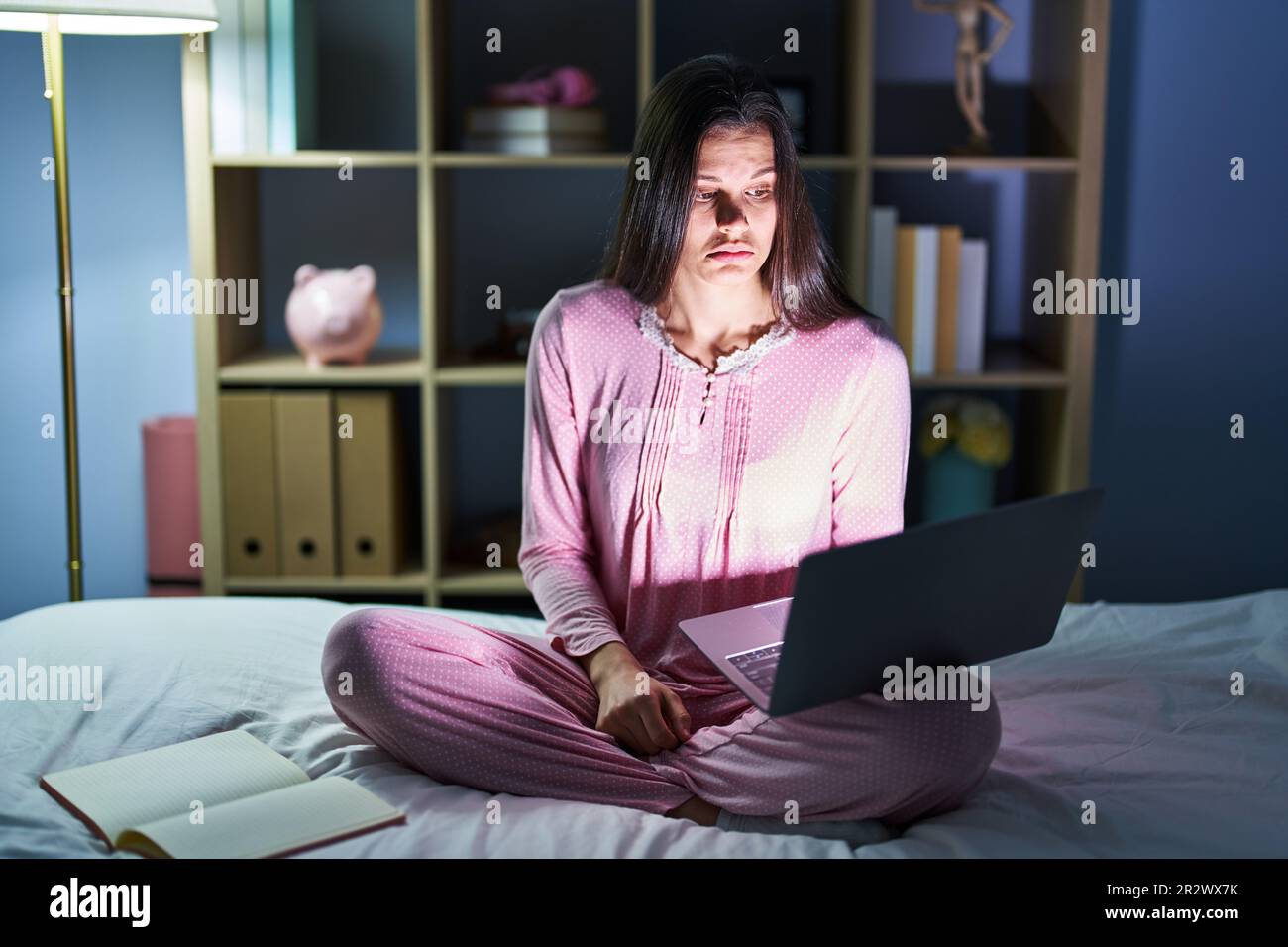 Young hispanic woman using computer laptop on the bed depressed and ...