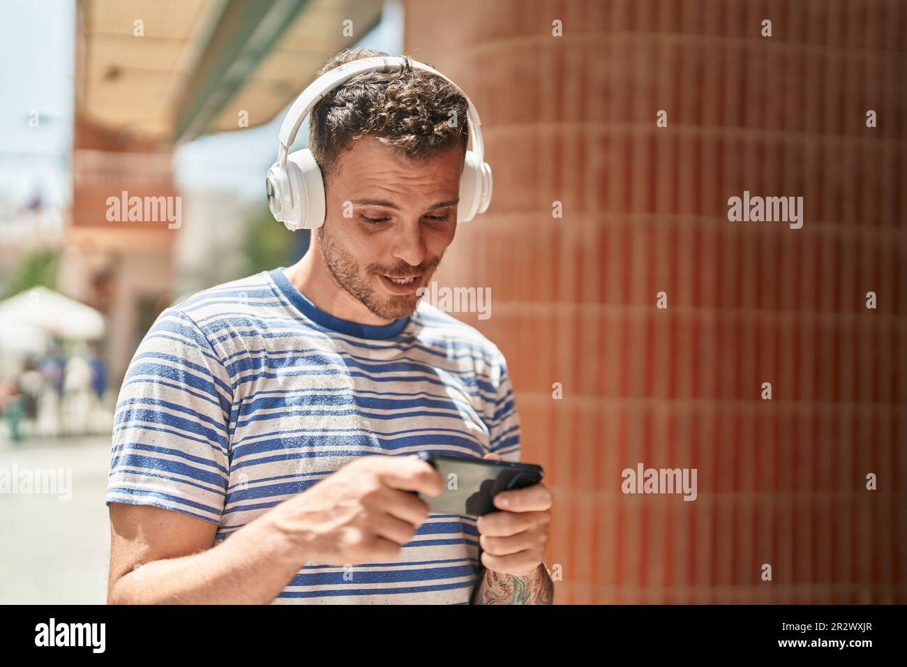 Young hispanic man smiling confident playing video game at street Stock ...