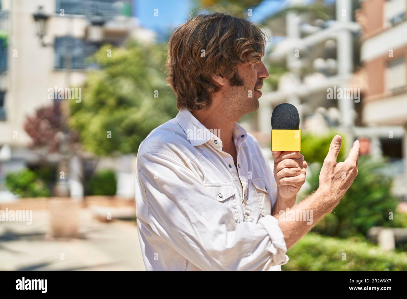 Young man reporter working using microphone at park Stock Photo - Alamy