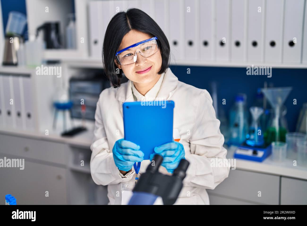 Young chinese woman scientist using touchpad working at laboratory ...